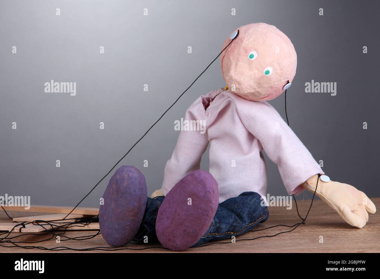 Wooden puppet sitting on grey background Stock Photo - Alamy