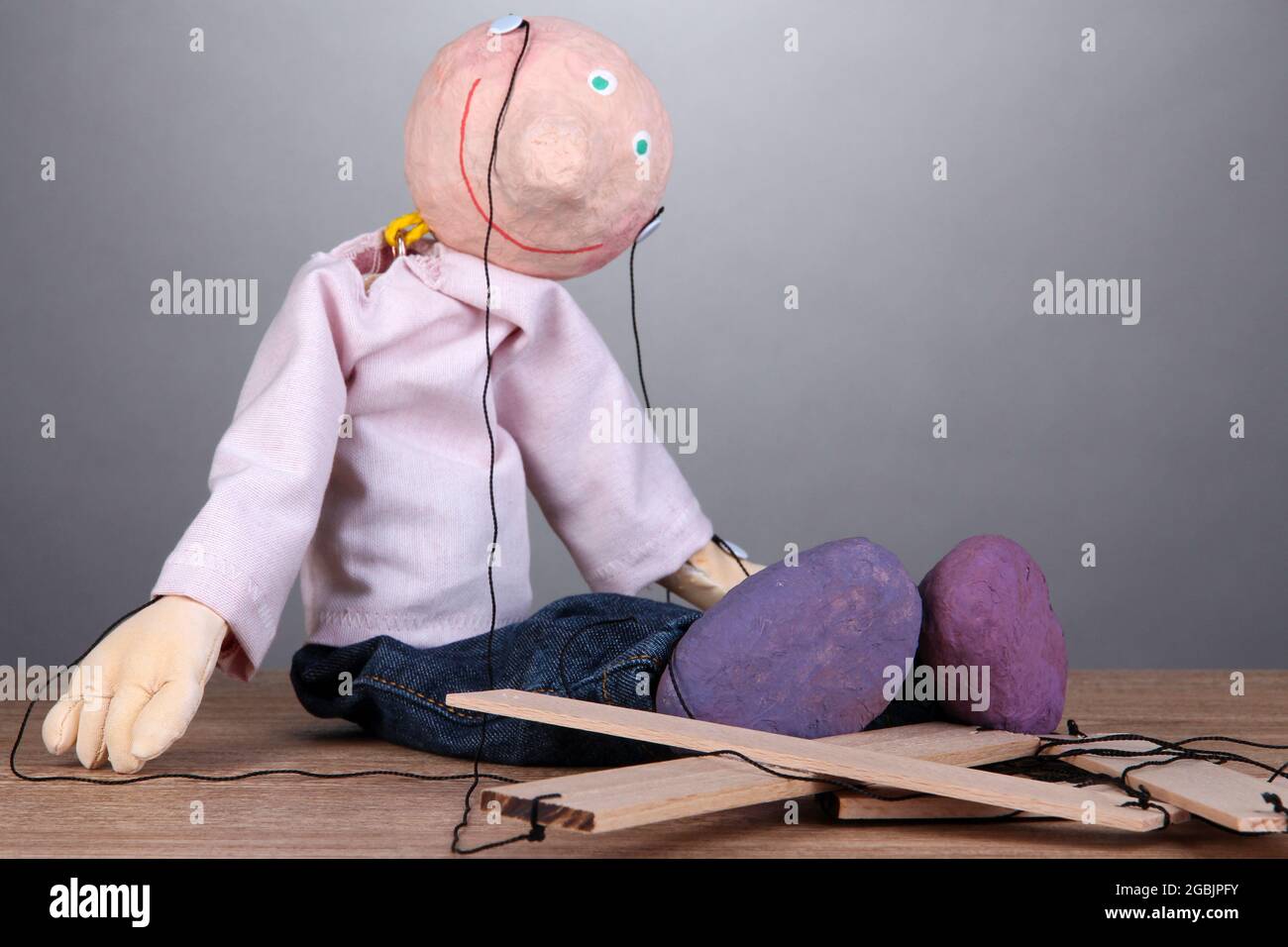 Wooden puppet sitting on grey background Stock Photo - Alamy