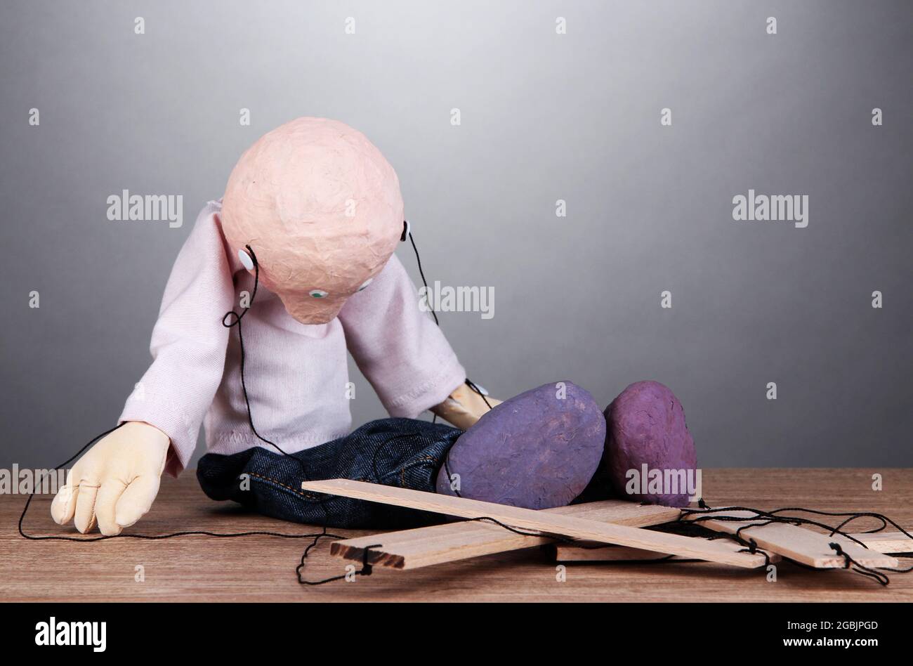 Wooden puppet sitting on grey background Stock Photo - Alamy