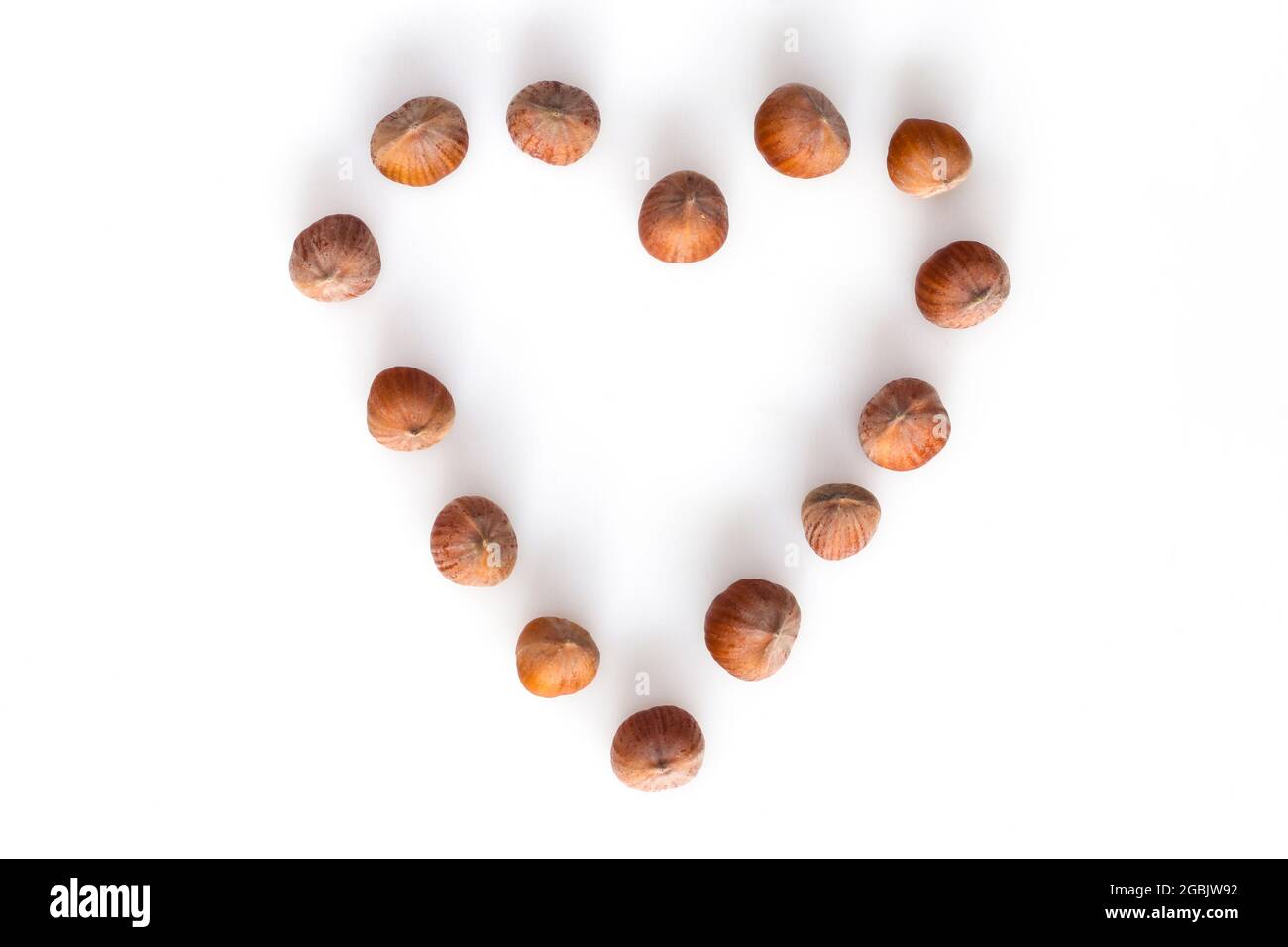 Heart shape made of whole hazelnuts on white background Stock Photo - Alamy