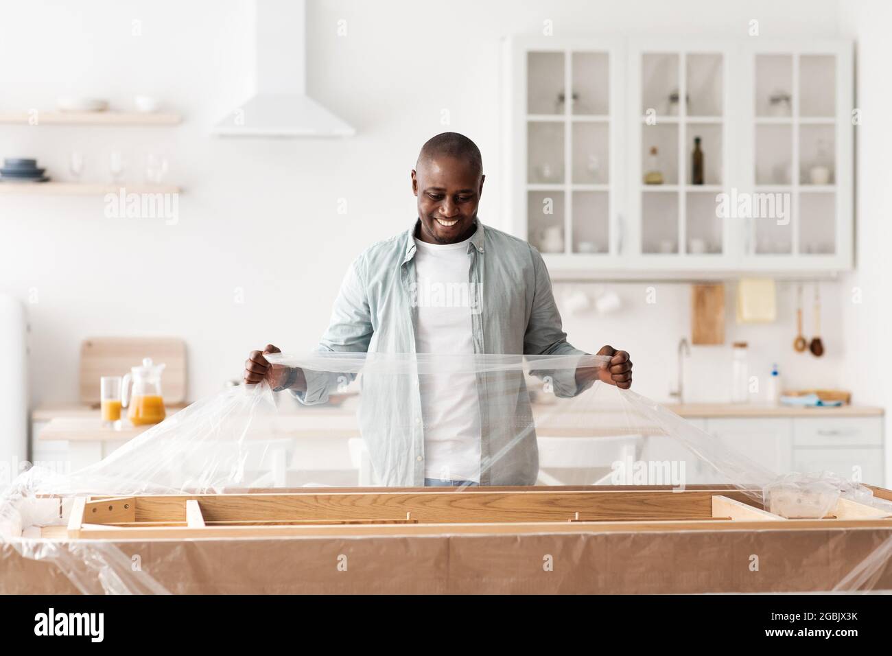 Moving, furniture and interior concept. Happy black man unpacking new ...