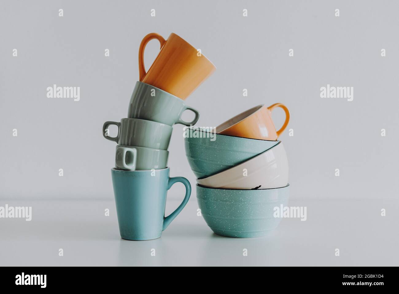 Group of cups, mugs, and bowls stacked on top of each other on a solid ...