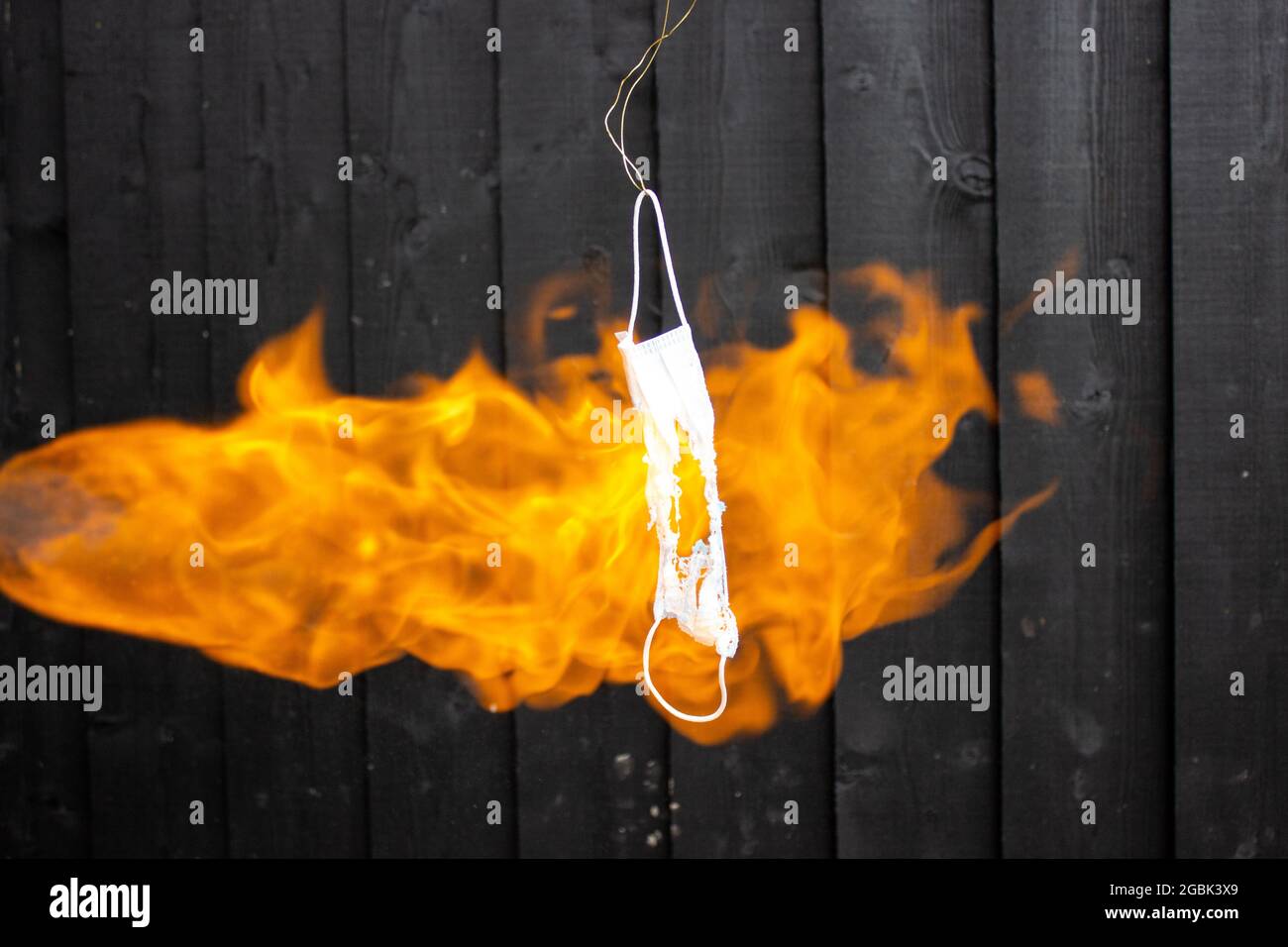 Burning single-use mask on a wooden wall background - lockdown lifted ...