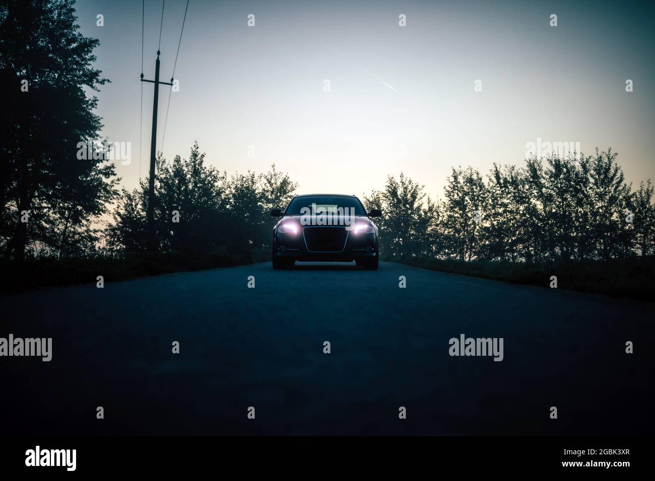 Low angle shot of a black car driving on an empty road at the sunrise ...