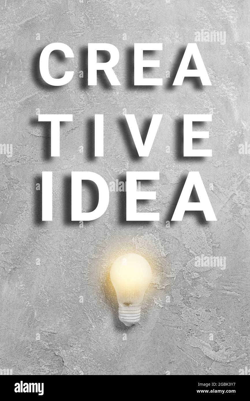 Creative idea text with glowing light bulb on gray background ...
