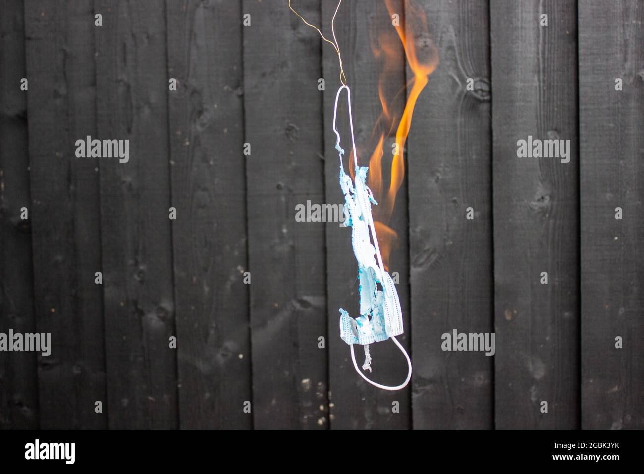 Burning single-use mask on a wooden wall background - lockdown lifted ...