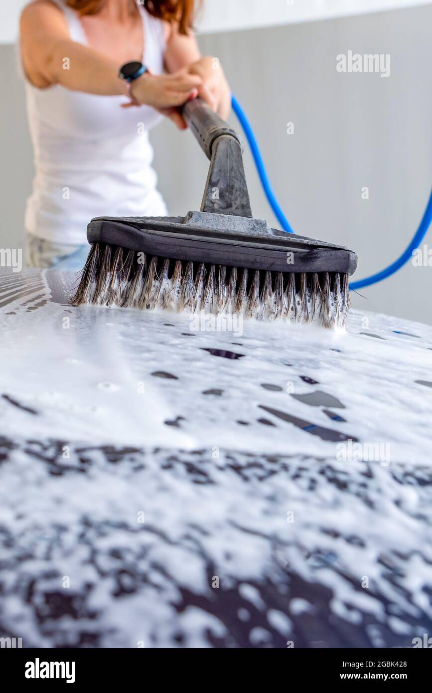 The woman washes the car. A woman at a car wash washes her car with a ...