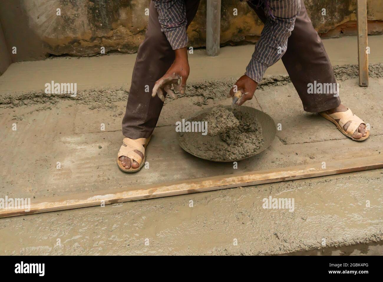 Indian construction workers plastering floor using trowel and cement ...