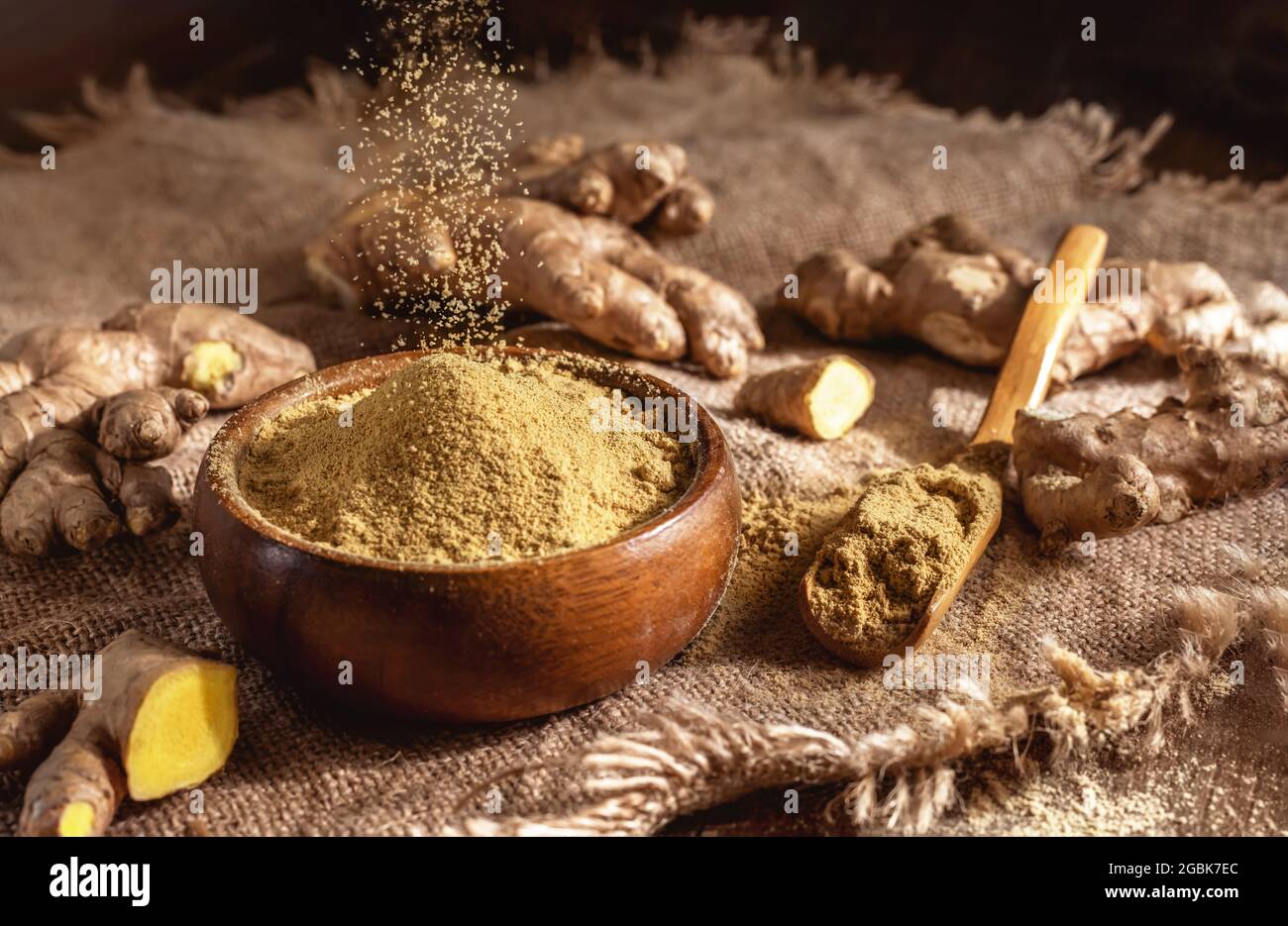 Fresh chopped ginger root and ground ginger powder in wooden spoon on ...