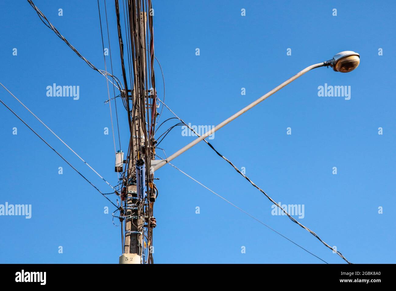 Street lamp post with emphasis on the tangle of wires and the blue sky ...