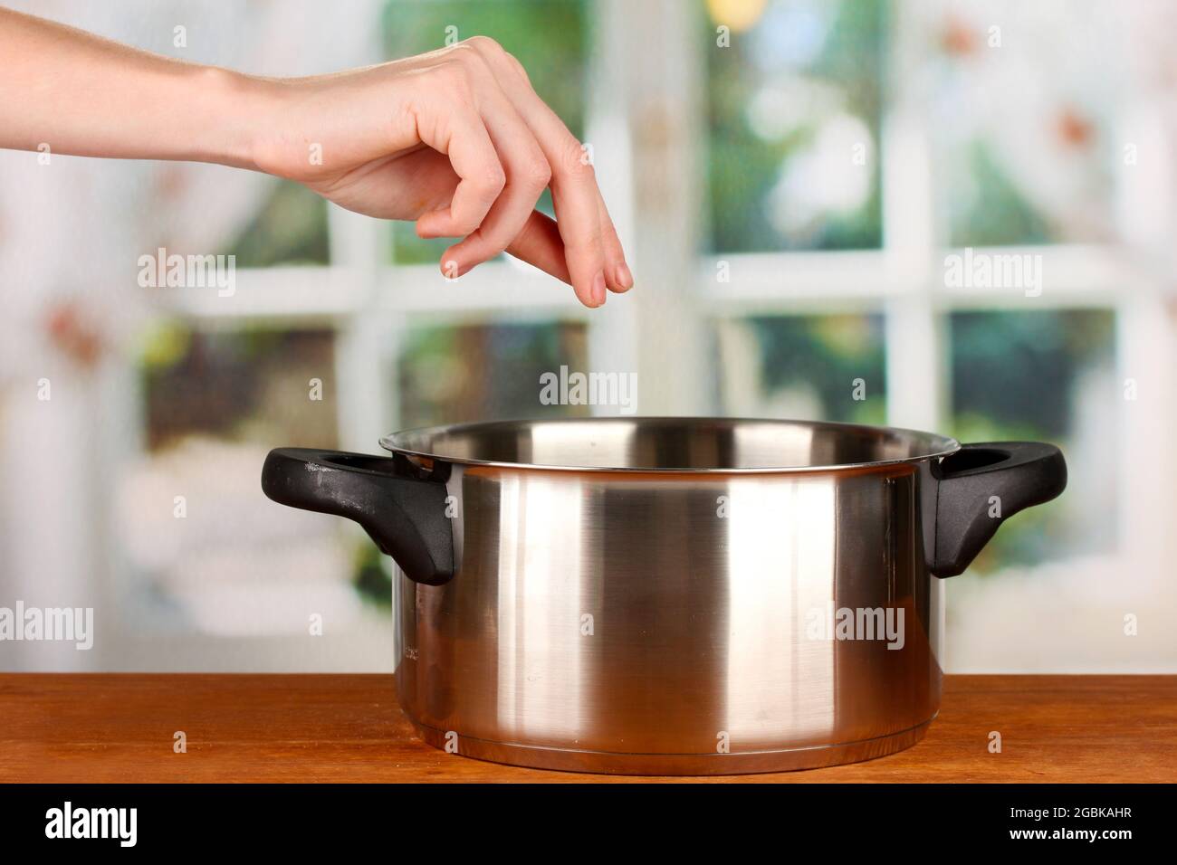 Hand adding salt on bright background Stock Photo - Alamy