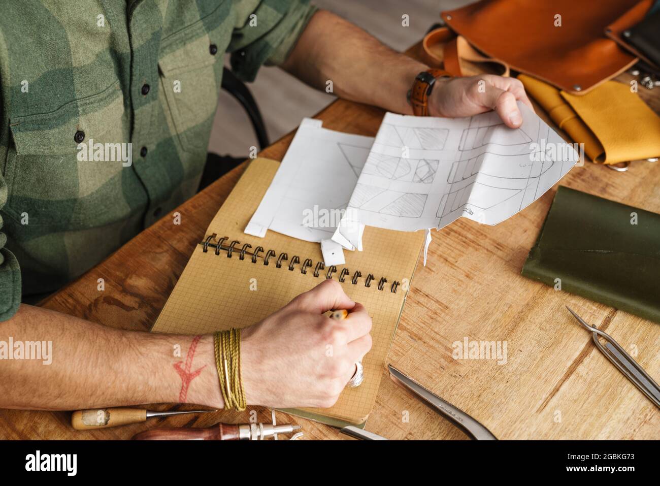 White craftsman drawing while working with leather in workshop Stock ...