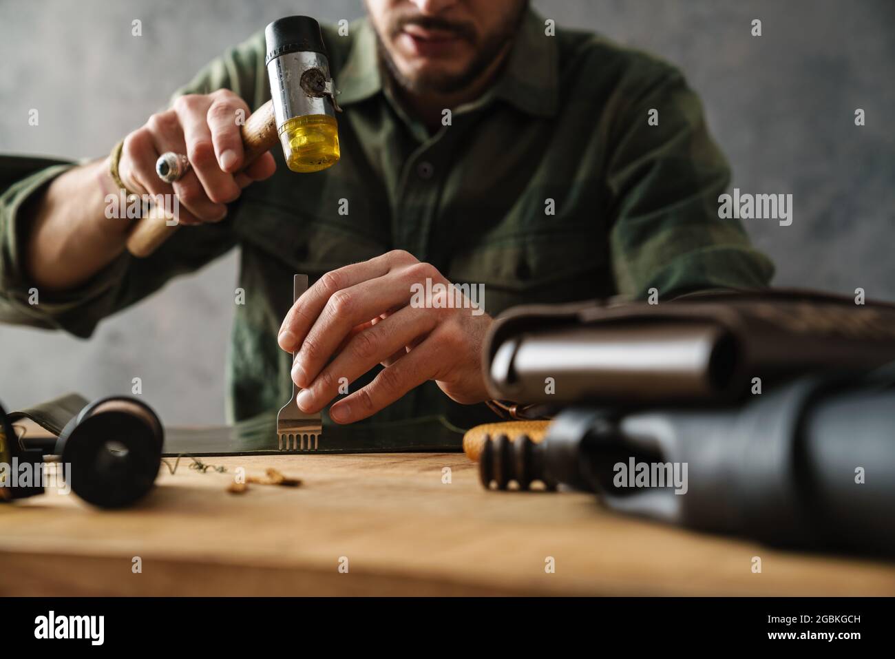 White craftsman using hummer while working with leather in workshop ...