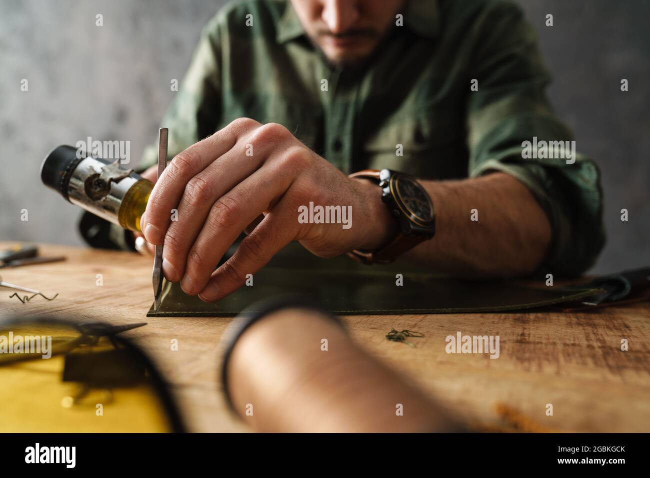 White craftsman using hummer while working with leather in workshop ...