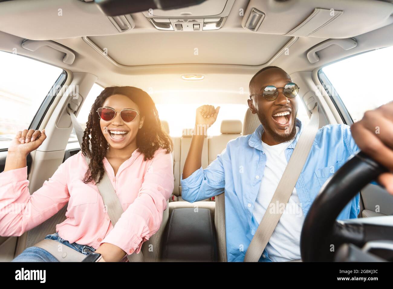 Happy black couple in sunglasses enjoying music driving luxury car ...