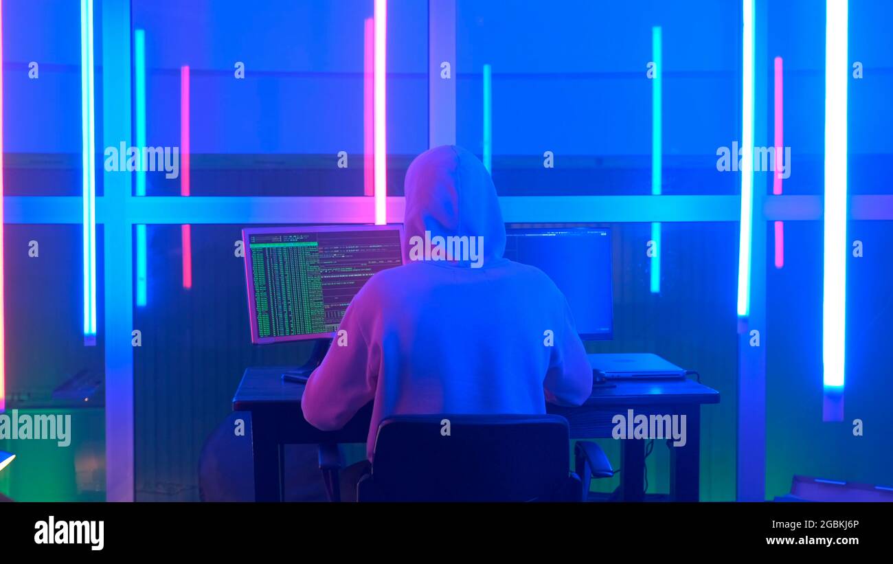 Medium back view shot of criminal hacker working in the evening on ...