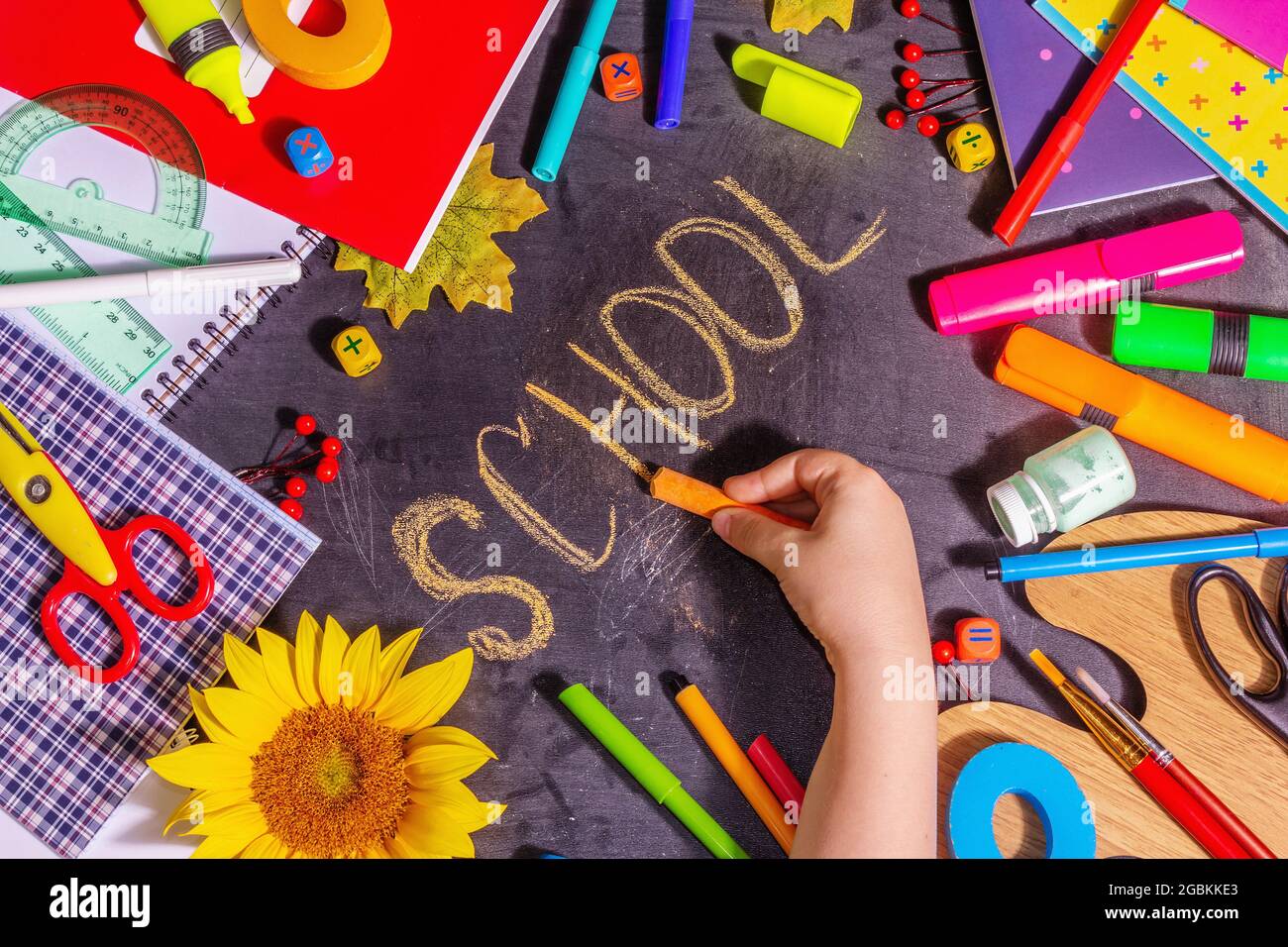 Children's hand writes the word "school" on a black chalkboard. School ...