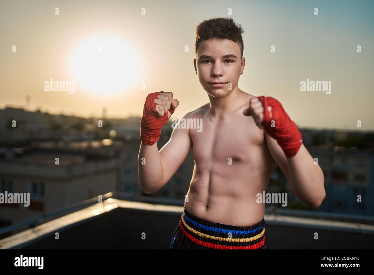 Young teenage kickboxer fighter training on the roof with buildings in ...