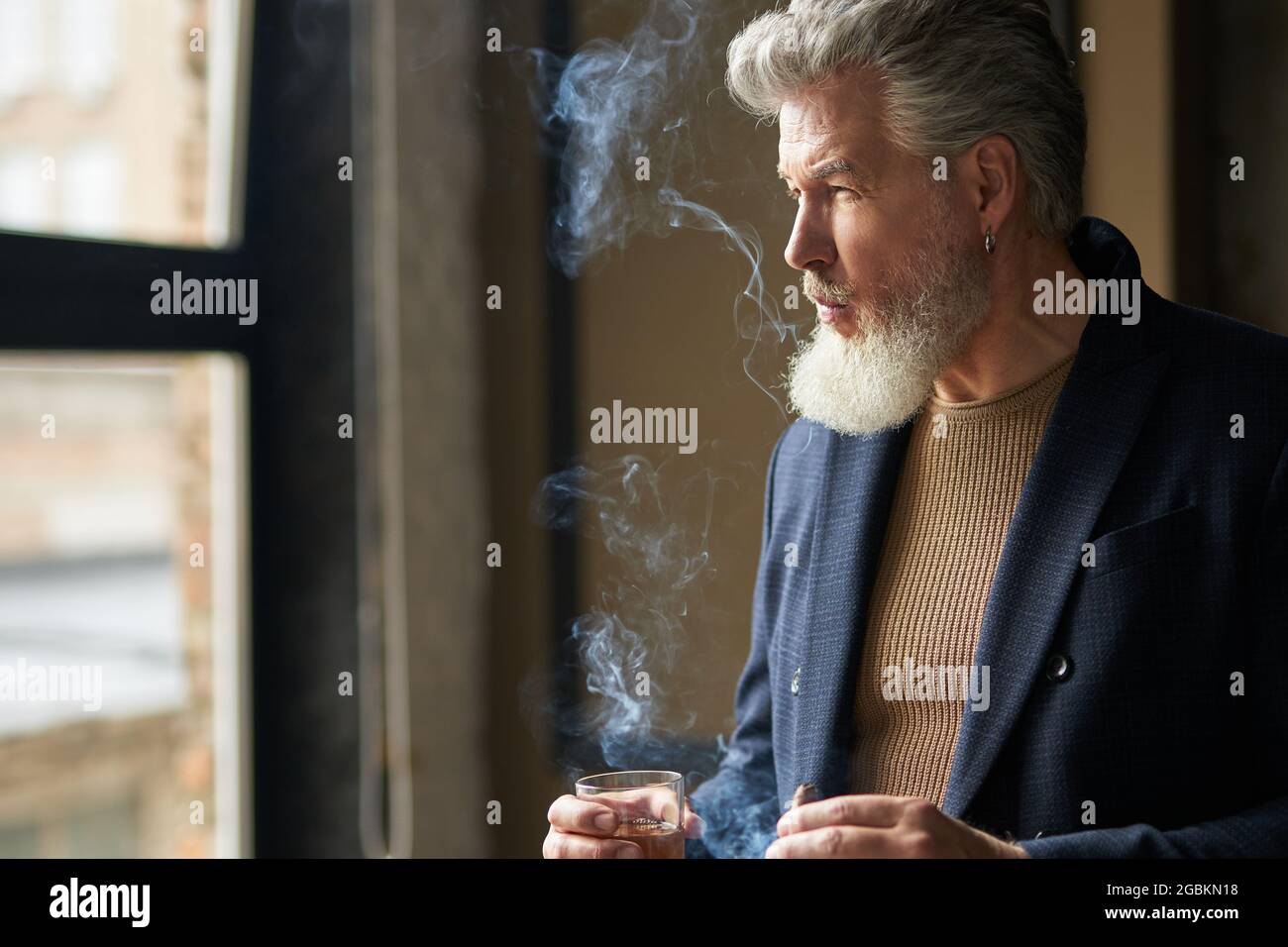 Stylish serious middle aged man with beard looking away while holding ...