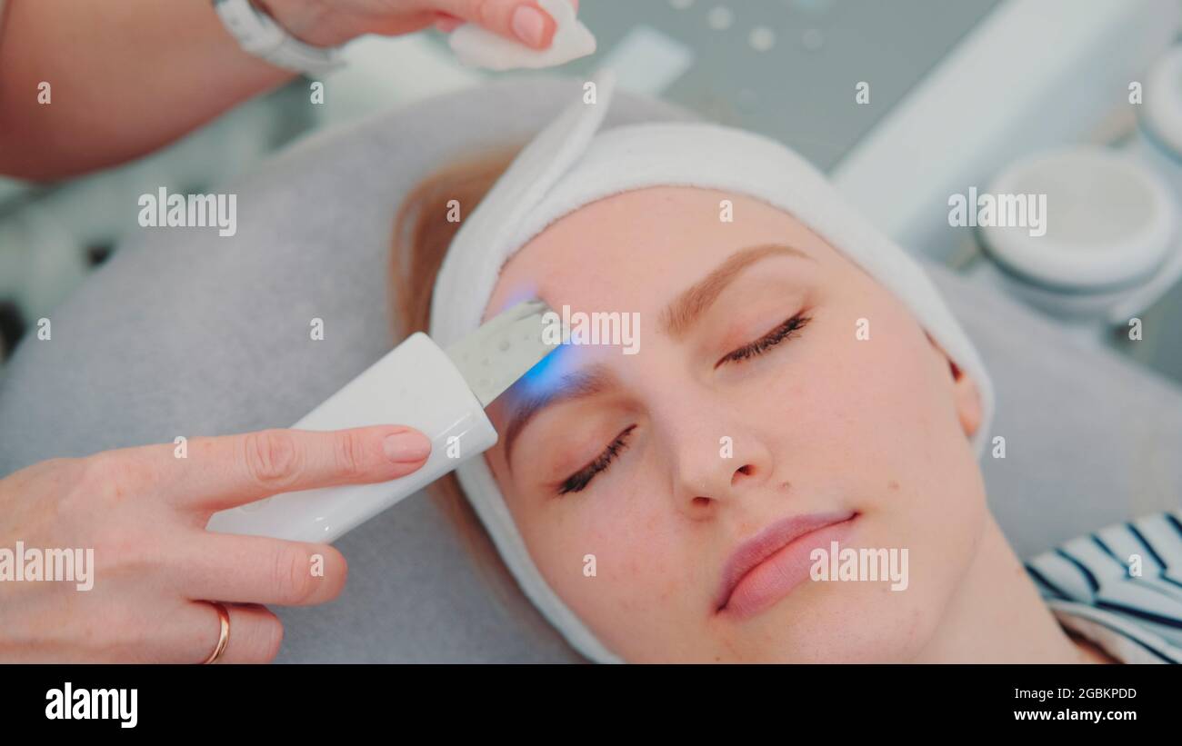 Close-up shot of cosmetician making cavitation facial peeling. Woman ...