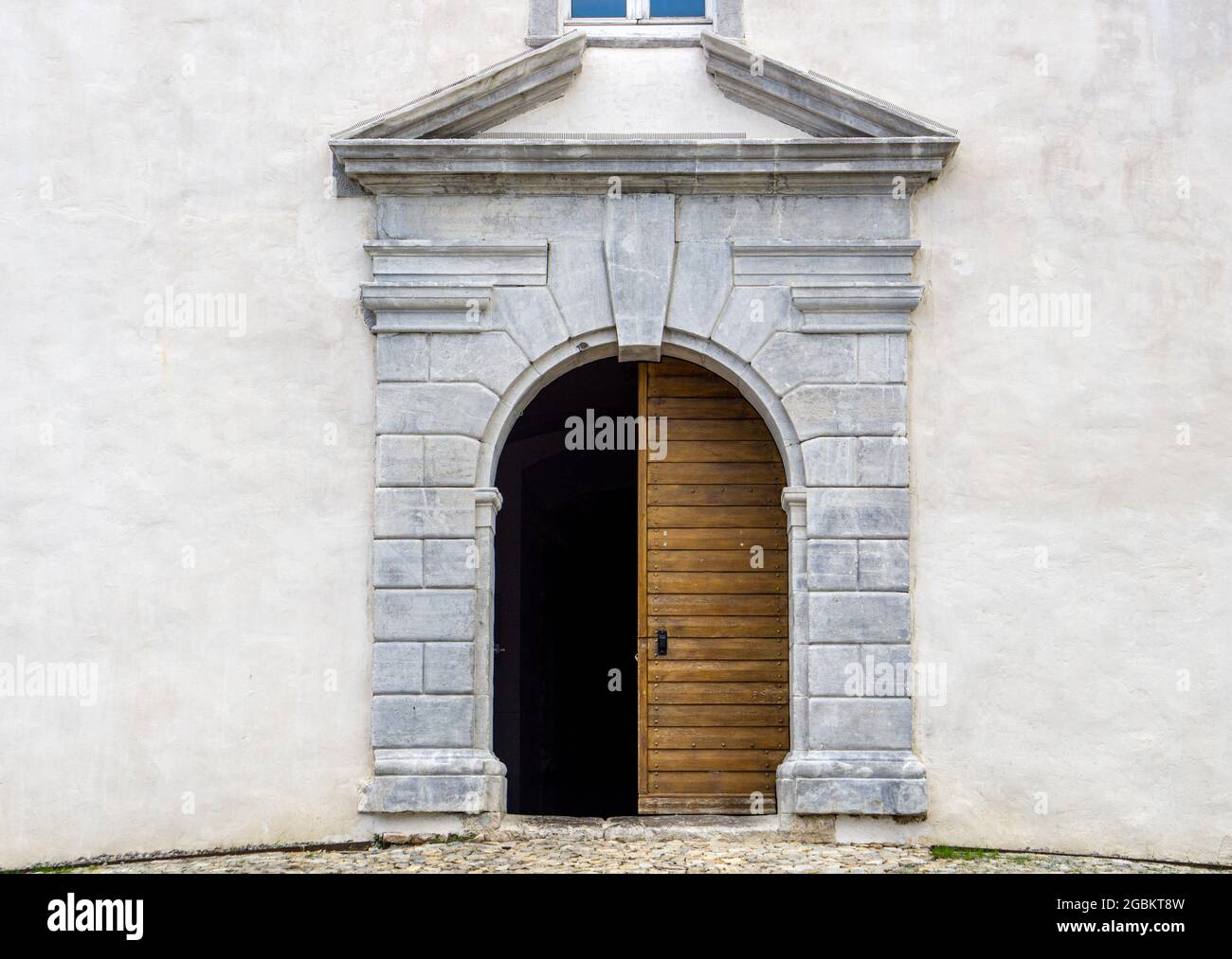Symmetric shot of a white building entrance with one open wooden door ...