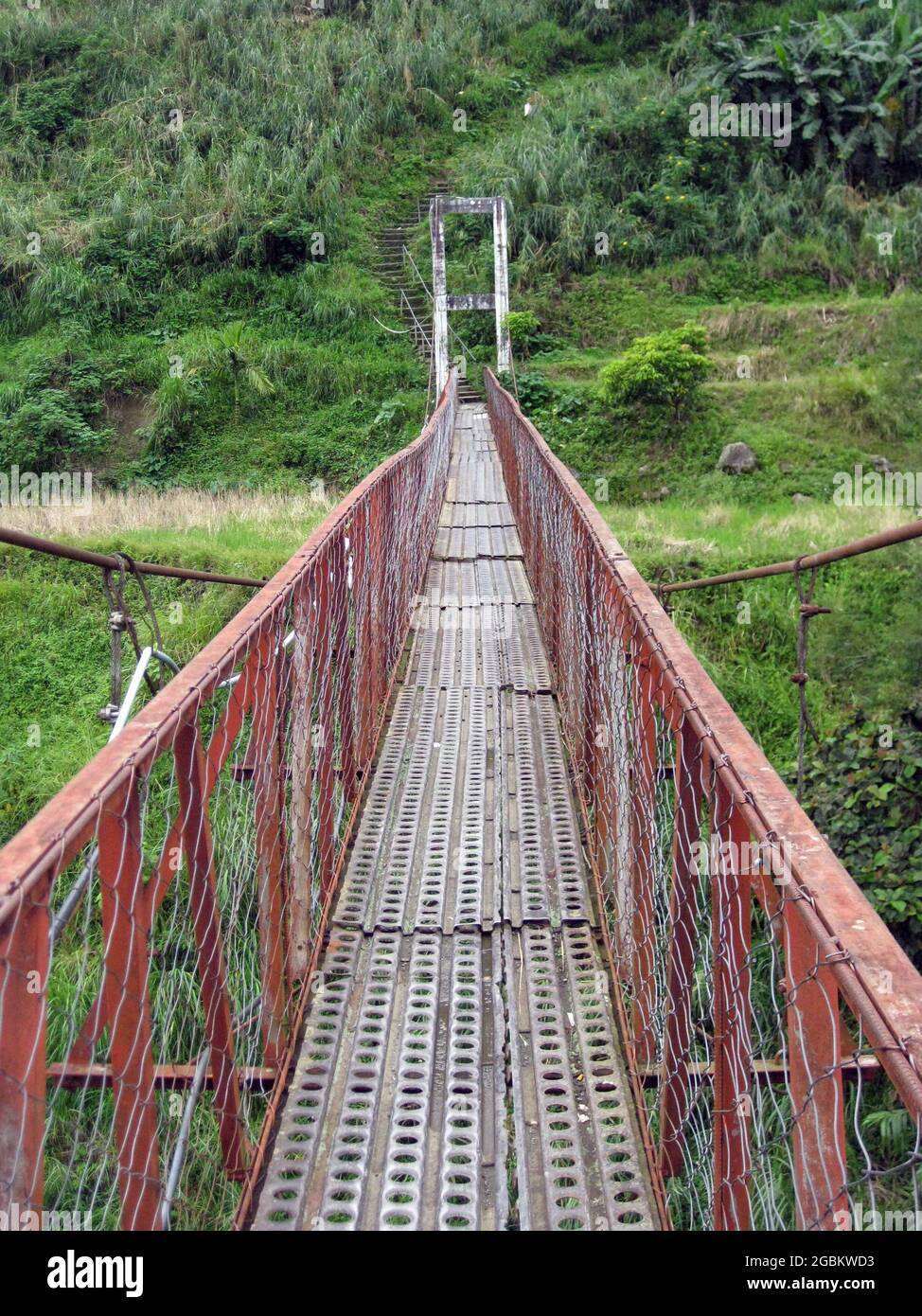 Vertical shot of a red metal bridge going to the hill with beautiful ...