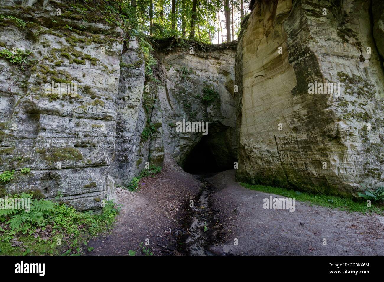 Nature object. White rocks with a deep black cave, from which flows ice ...