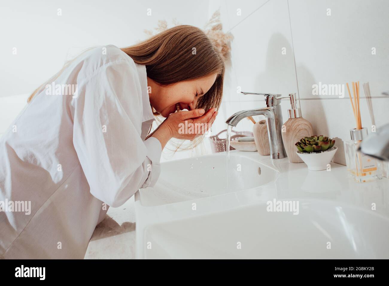 Woman splashing face with water over bathroom sink Stock Photo - Alamy