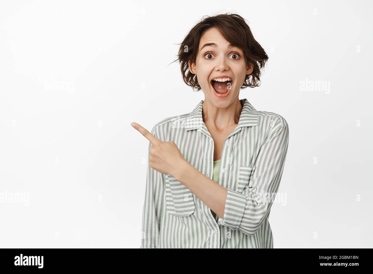 Portrait of excited brunette woman pointing finger left, sale promo ...