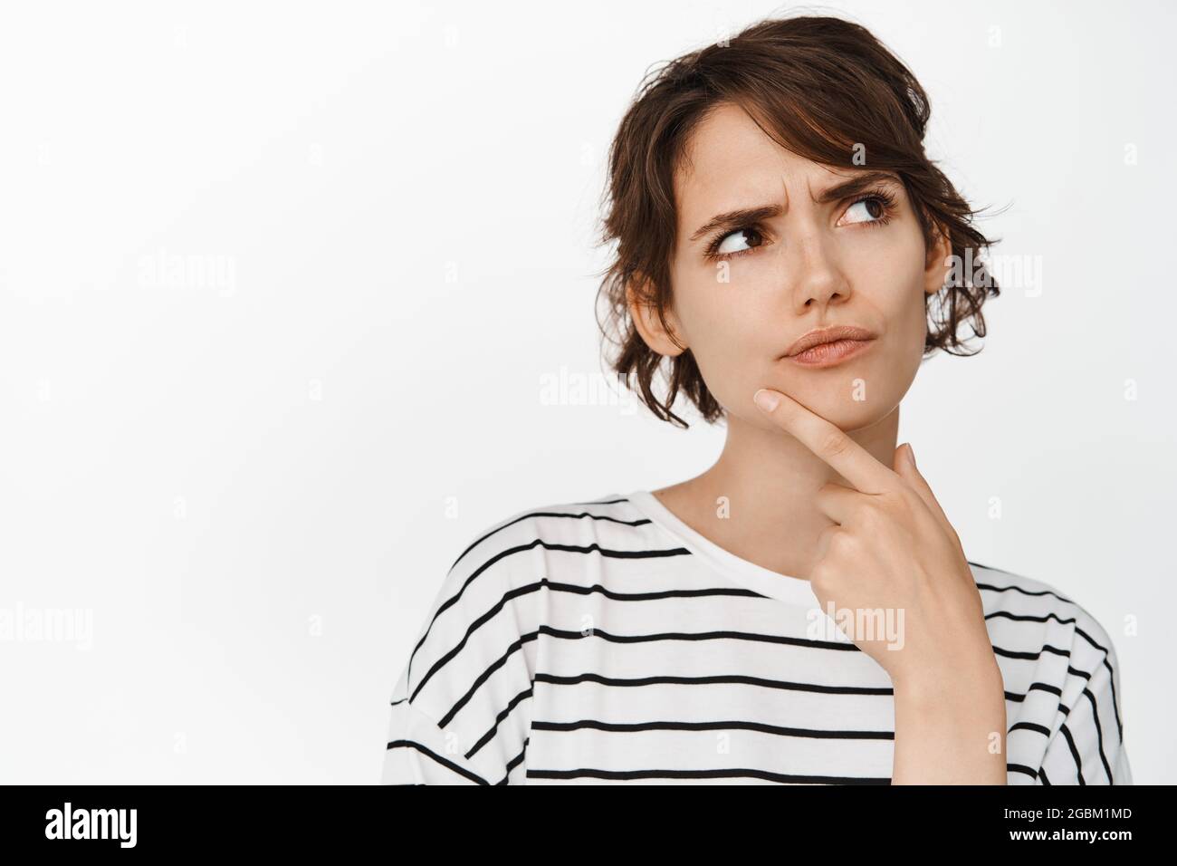 Hmm let me think. Thoughtful brunette woman frowning puzzled, looking ...