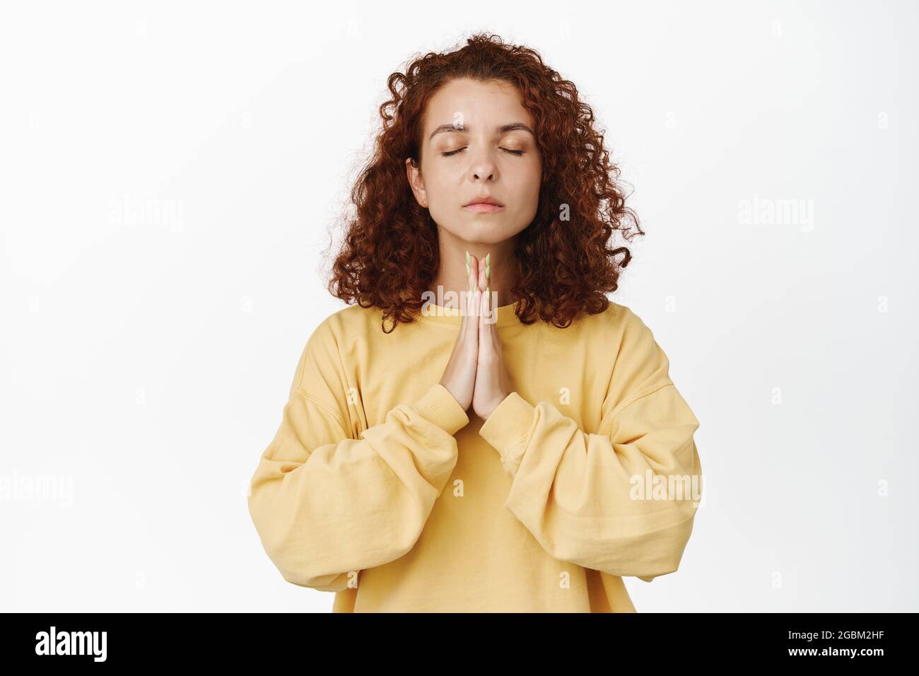 Calm young redhead woman, mindful girl meditating, showing namaste ...