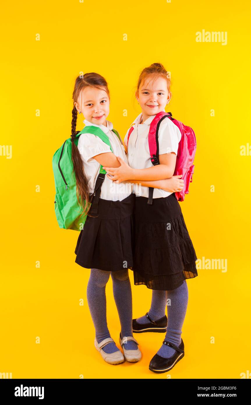 Two girls classmates are hugging on a yellow background Stock Photo - Alamy