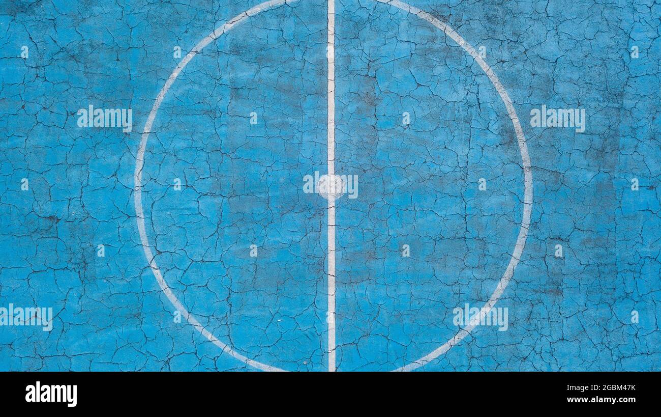 Multi-sport court with a central circle and a floor painted blue and ...