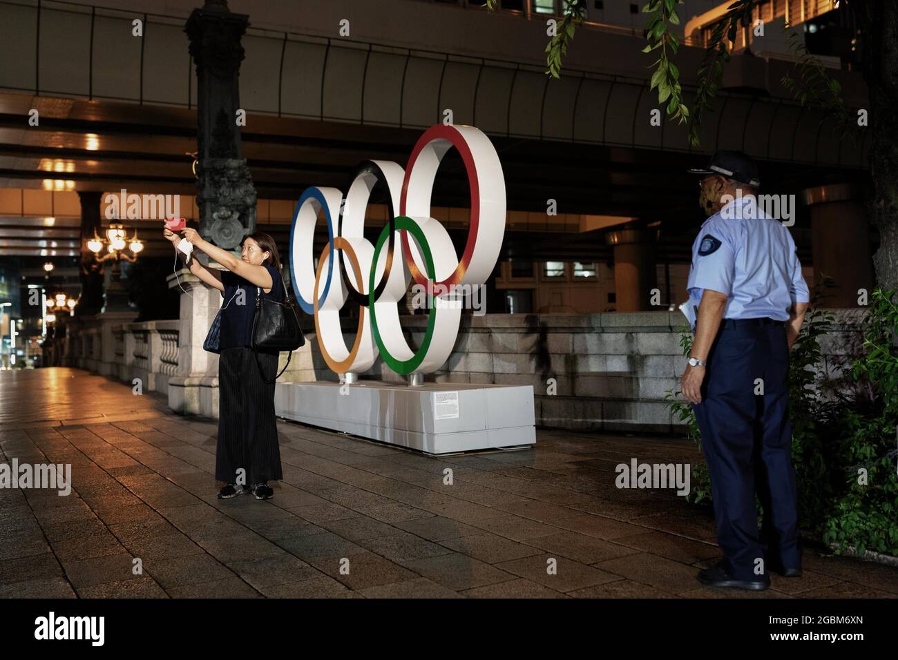 A security guard looks at a woman taking a selfie in front of the ...