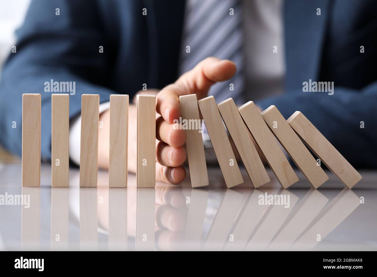 Business man in suit holding with hand falling sequence of wooden ...