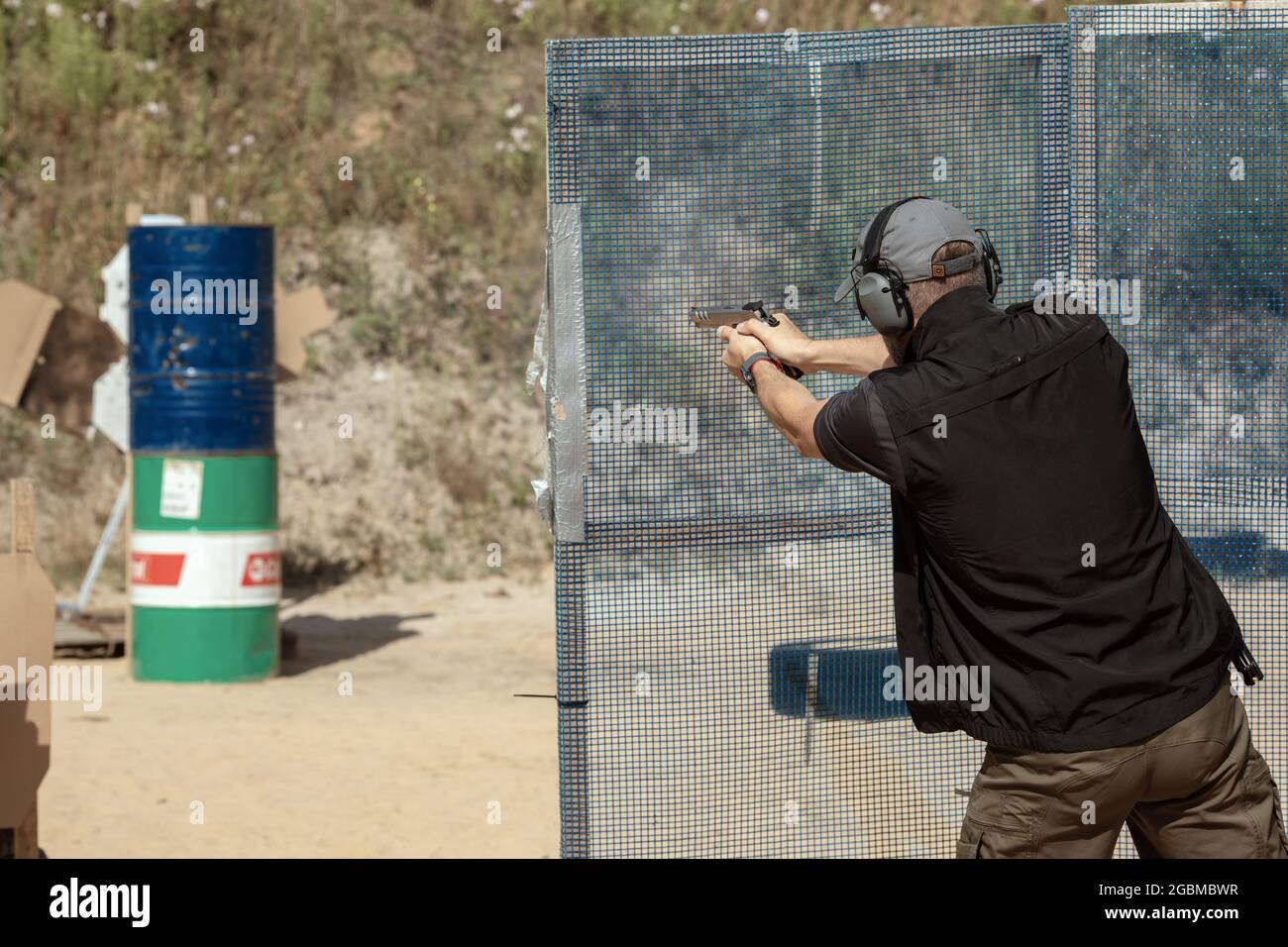 Man in tactical clothes shooting from a pistol, reloading the gun and ...