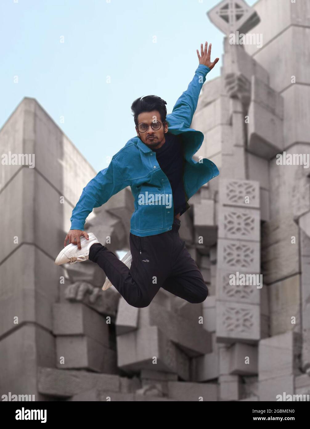 Vertical shot of a South Asian male jumping and posing in a historic ...