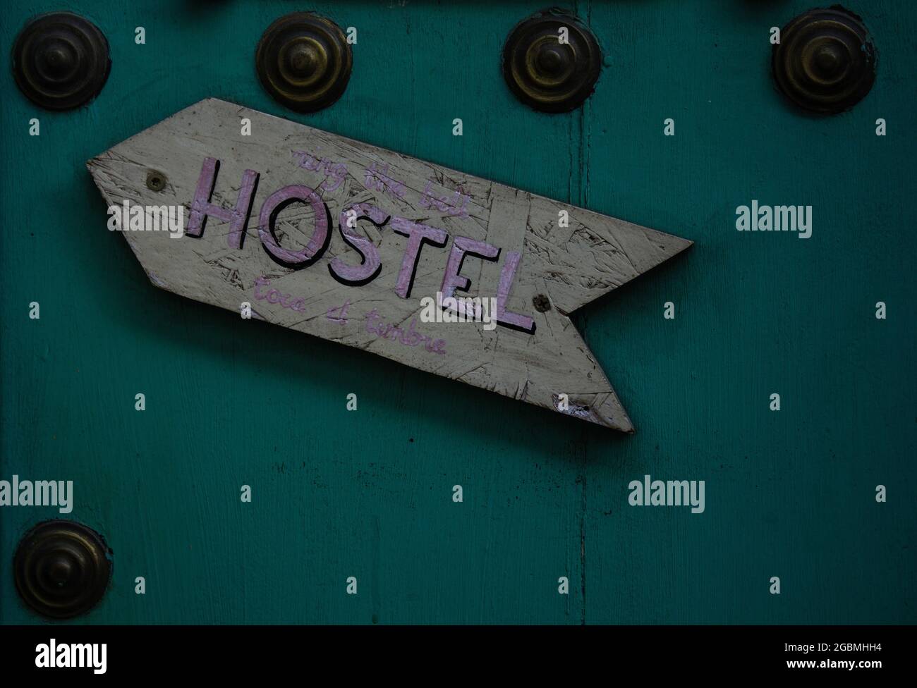 Wooden direction sign to the hostel on the wall with metal round ...