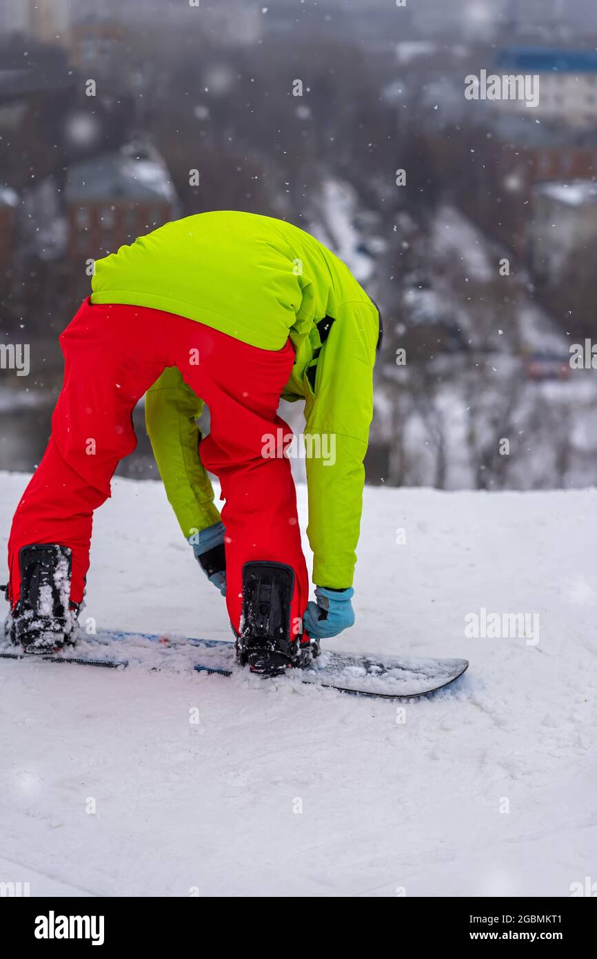 Back view of Snowboarder attaches Snowboard on ski slope. Winter sport ...