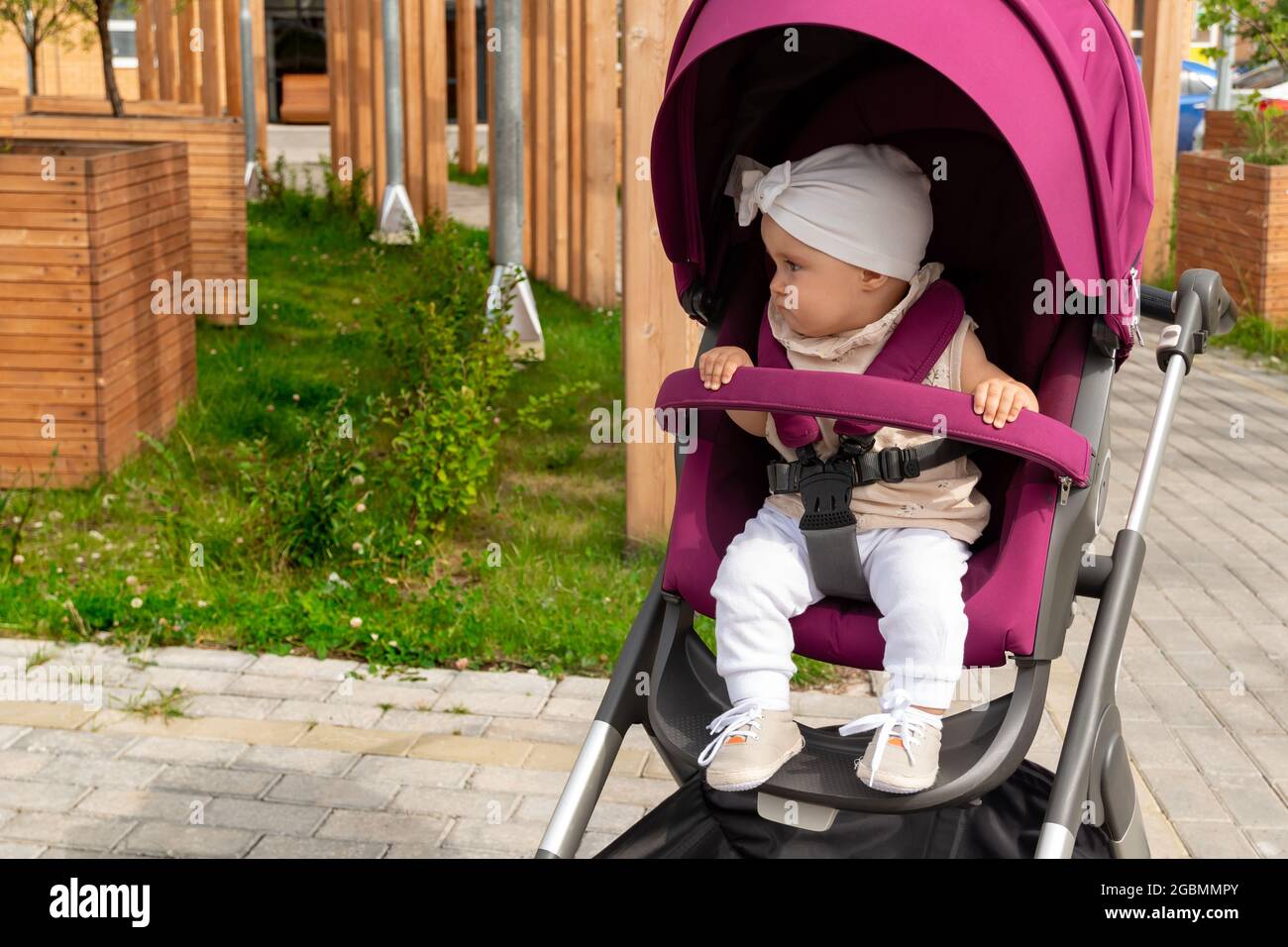 baby girl sits in a stroller and wants to go on her own Stock Photo - Alamy