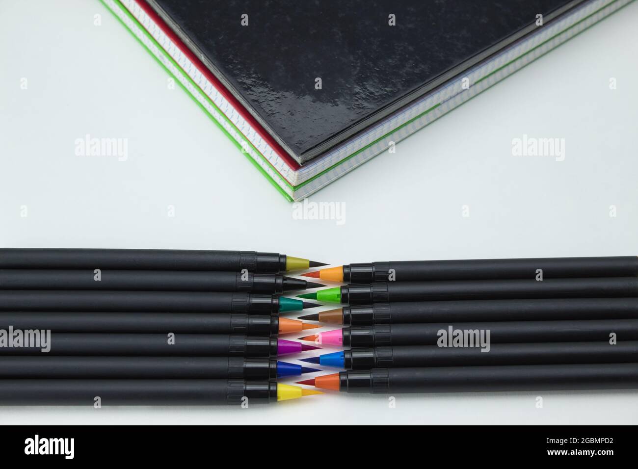 foreground of set of colored self-tips pens and markers and notebooks ...