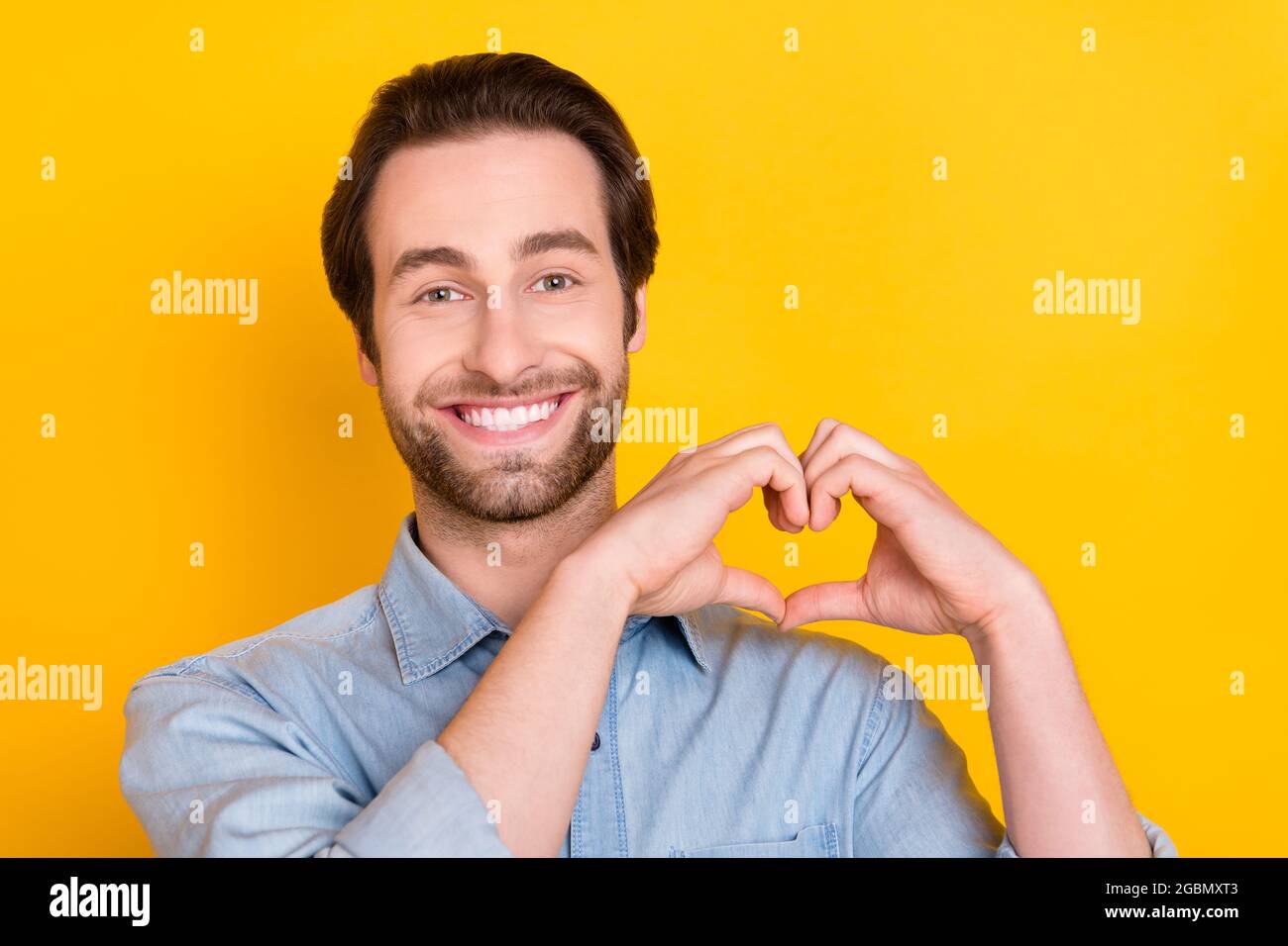Photo portrait of young guy smiling showing heart shaped gesture ...