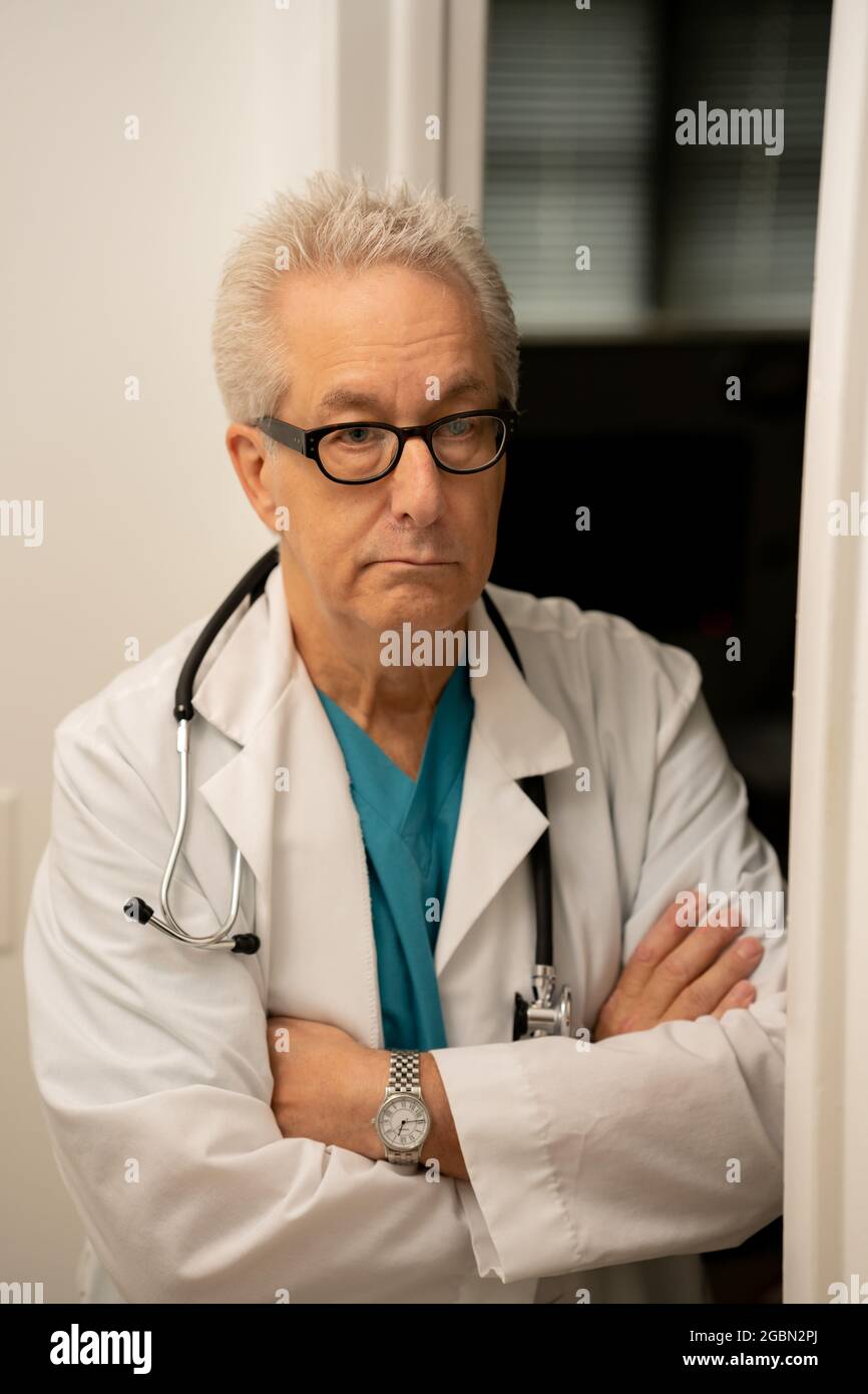 Doctor standing by an open door with arms crossed deadpan expression ...