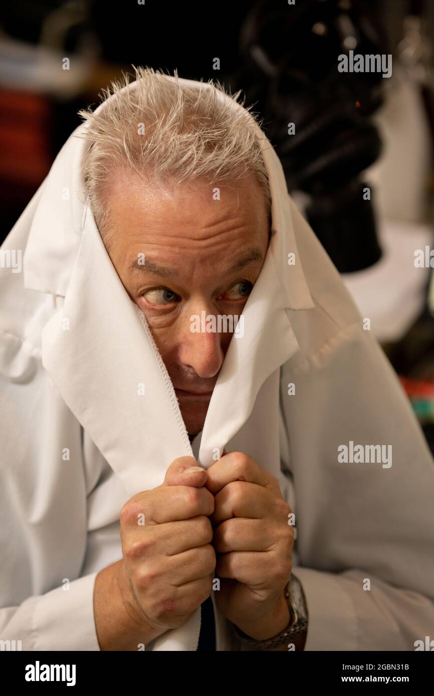 Photo of a doctor hiding under his lab coat in fear Stock Photo - Alamy