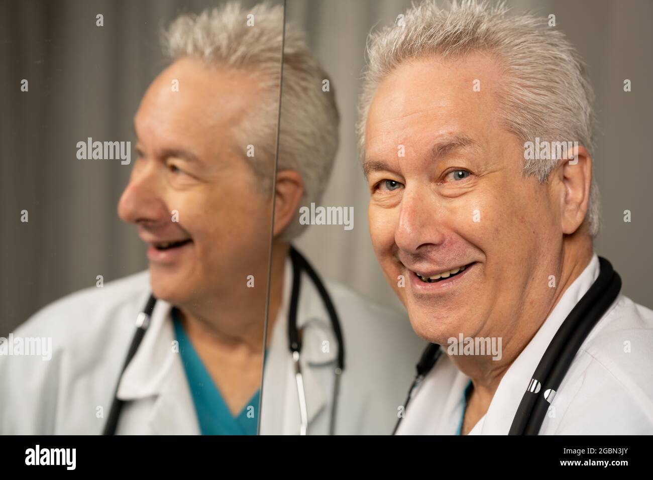 Doctor smiling over shoulder with reflection in the mirror Stock Photo ...