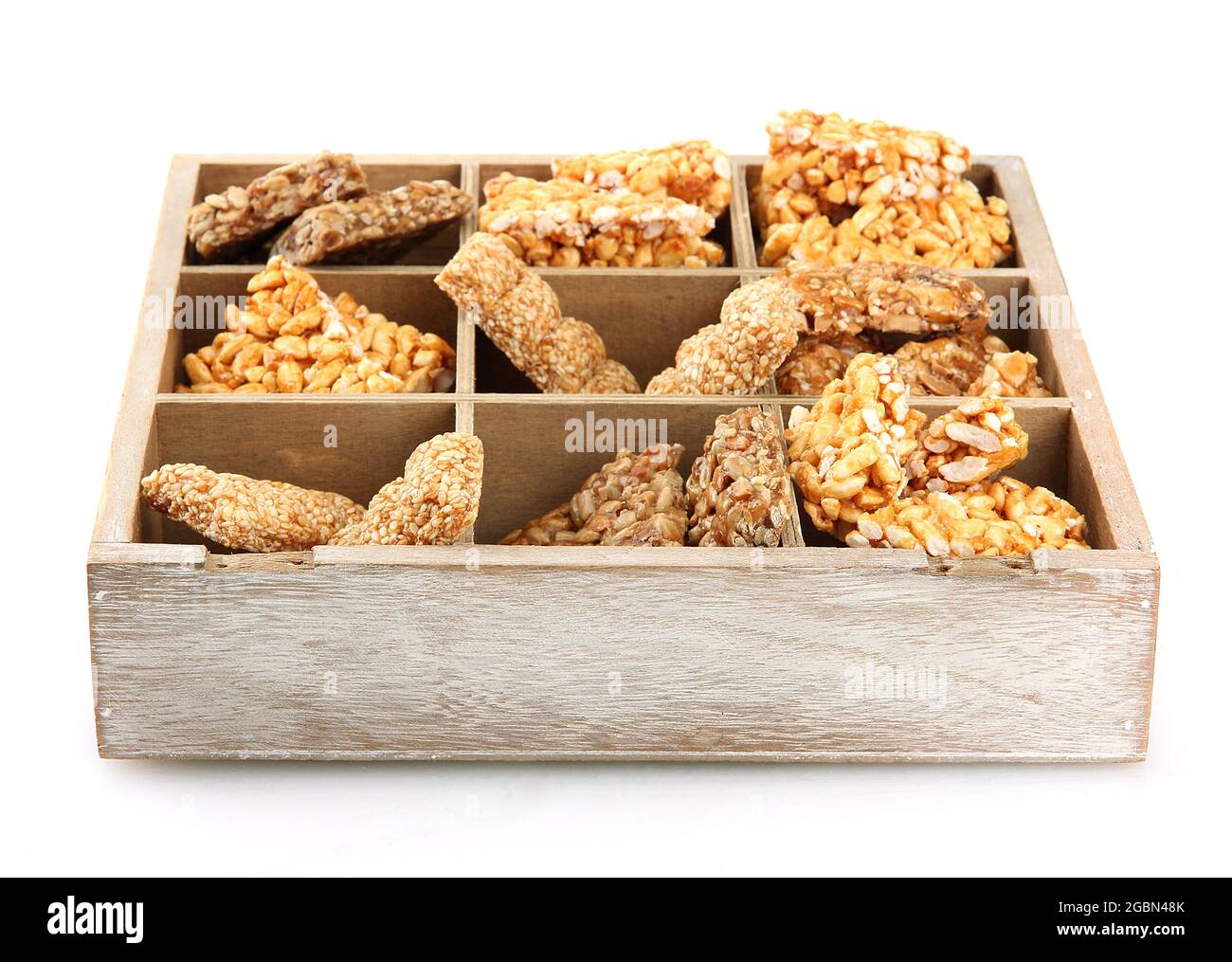 tasty sweets (kozinaki)in wooden crate, isolated on white Stock Photo ...