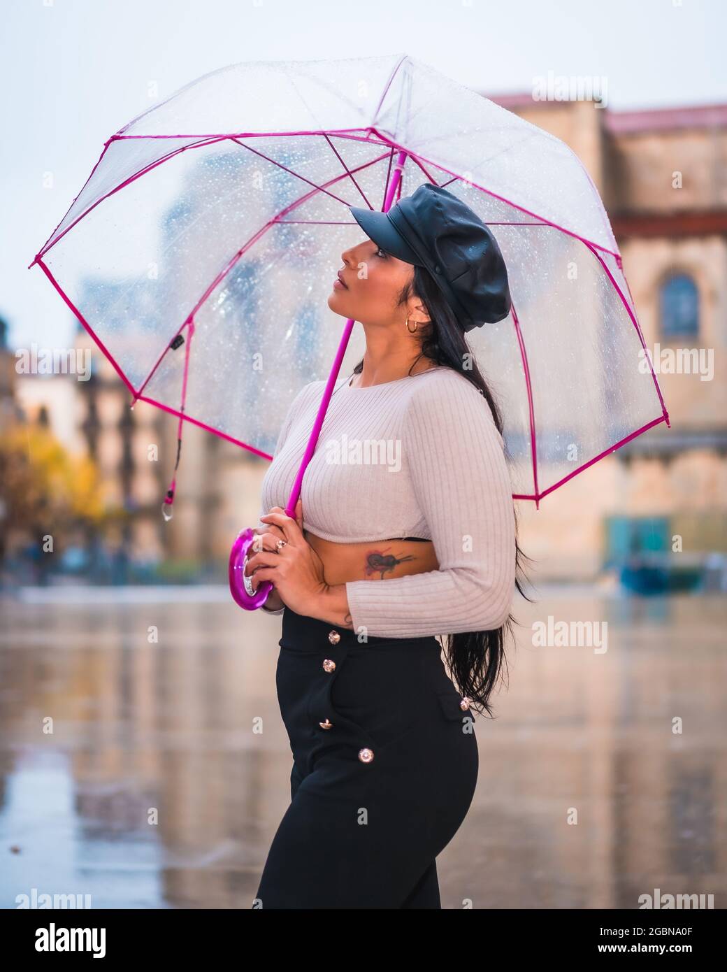 Woman standing under the rain in the street with an umbrella and ...