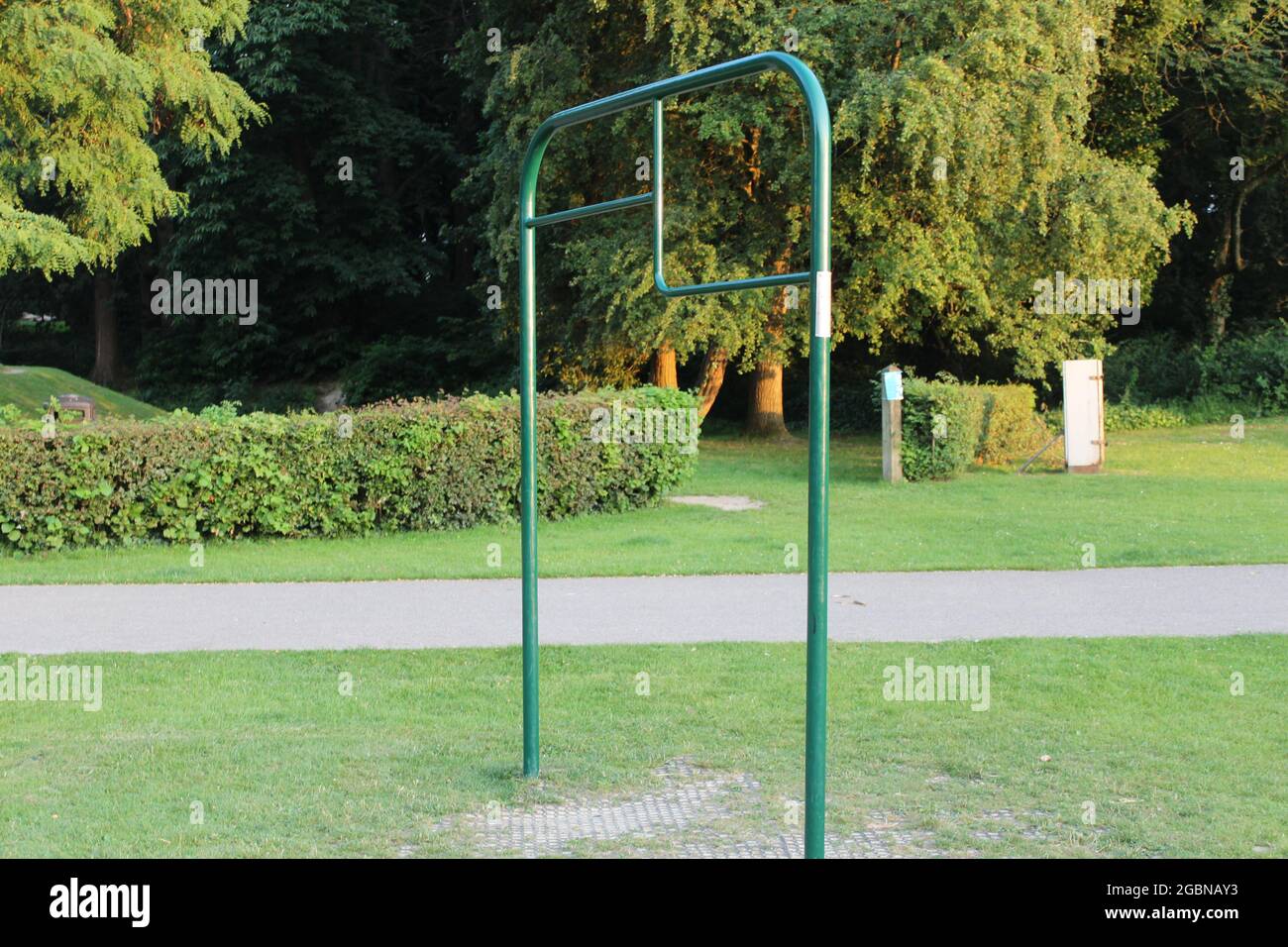 Green pull-up bar in a park covered in greenery unde the sunlight Stock ...