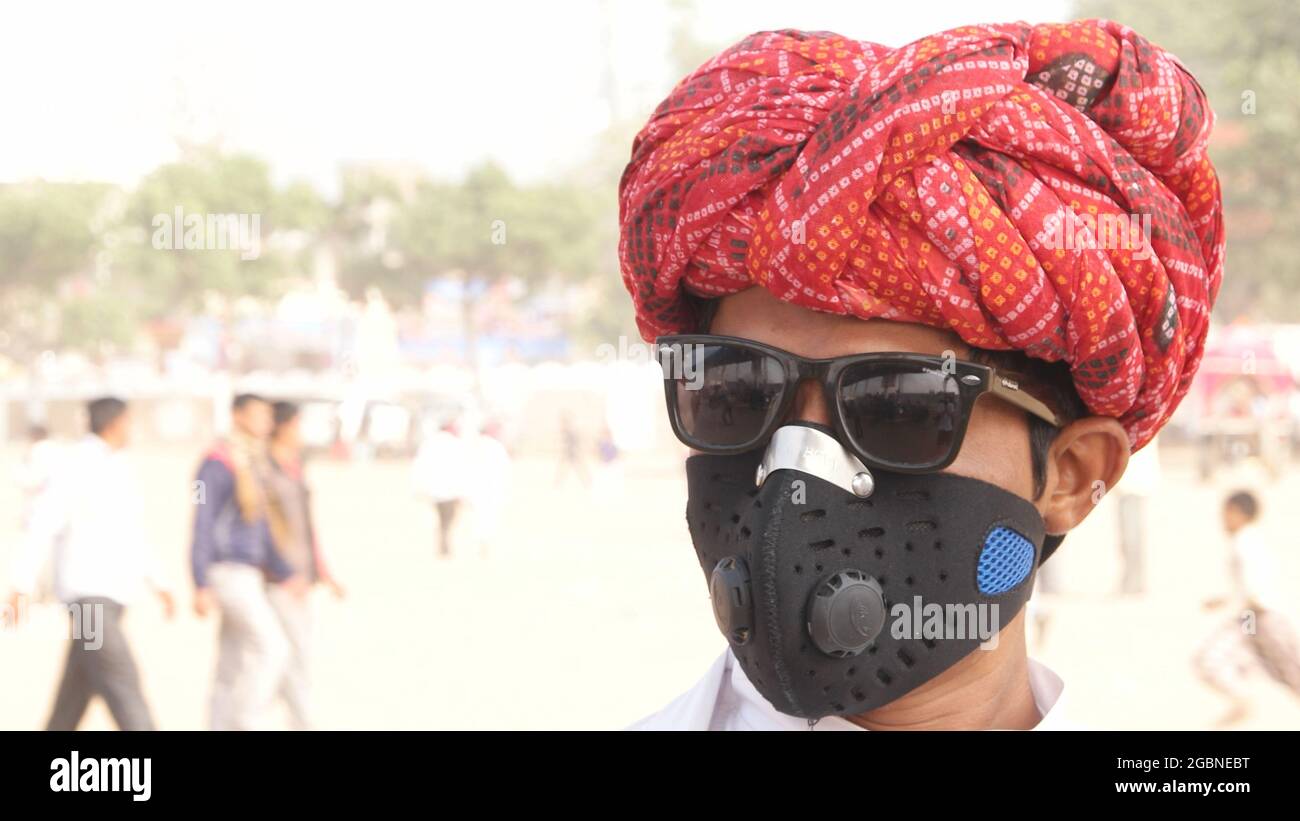 Young Indian man in traditional clothes and facial mask walking outdoor ...