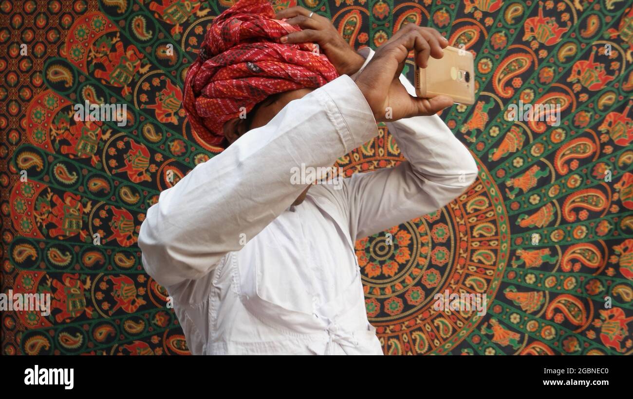Young Indian man in traditional clothes and turban taking pictures ...